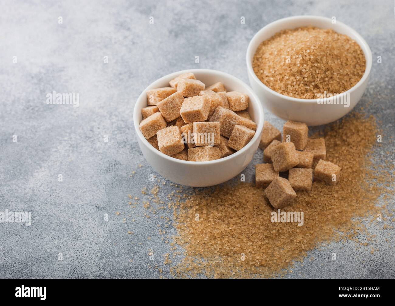 White bowl plates of natural brown sugar cubes and refined sugar on ...