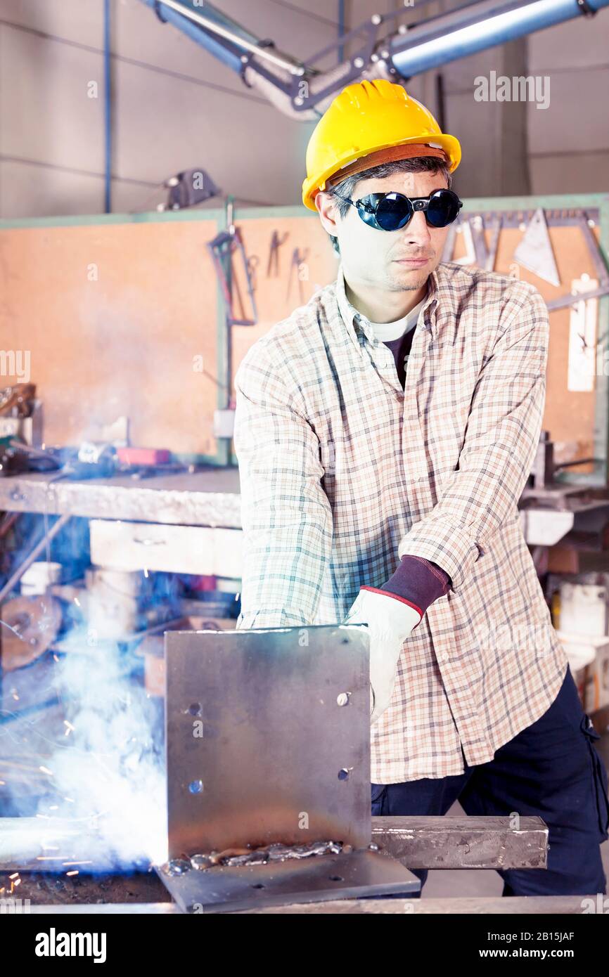 young worker while welding in a steel mill Stock Photo - Alamy