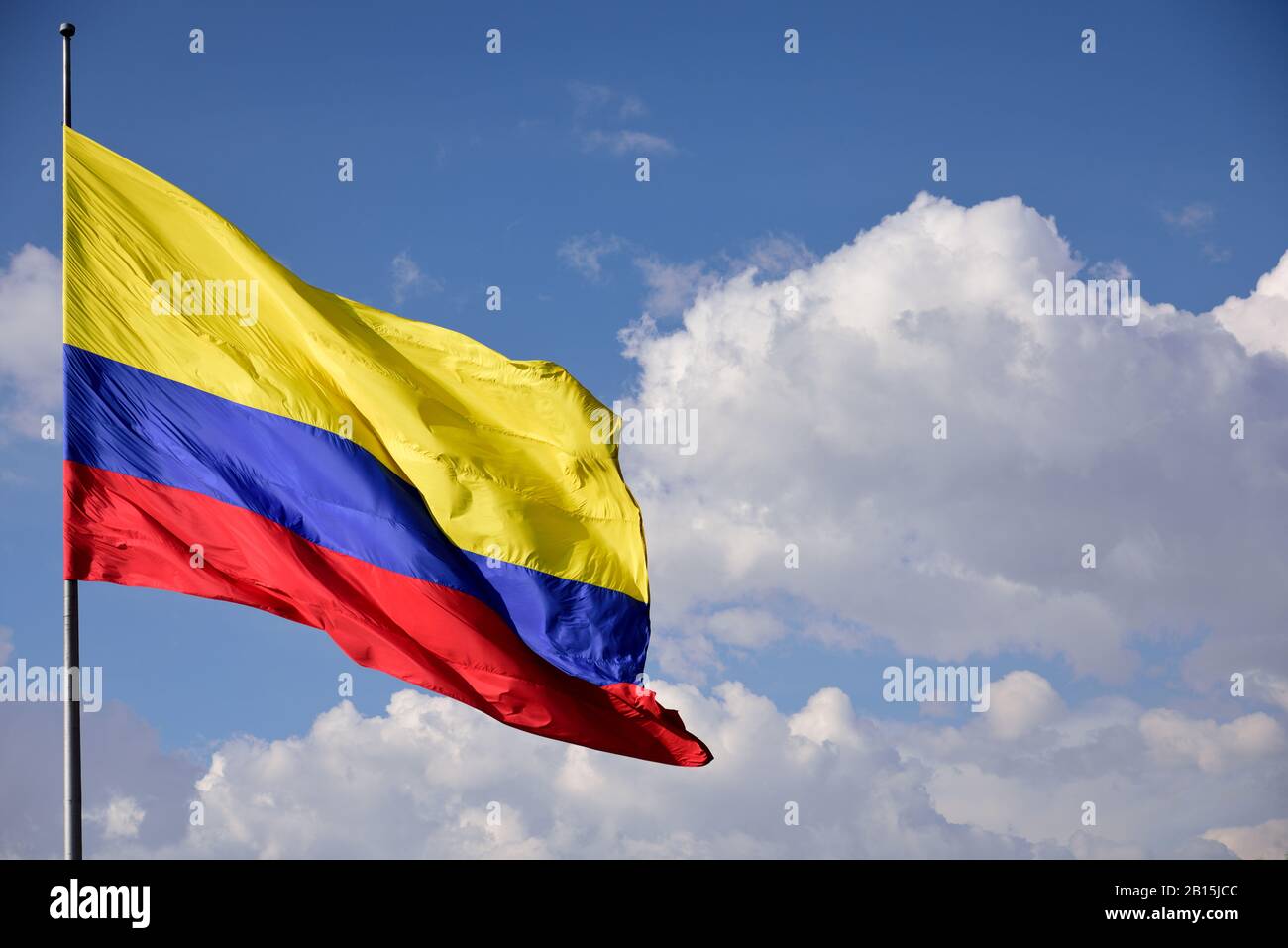 Large national flag of Colombia atop flag pole, isolated with sky and ...