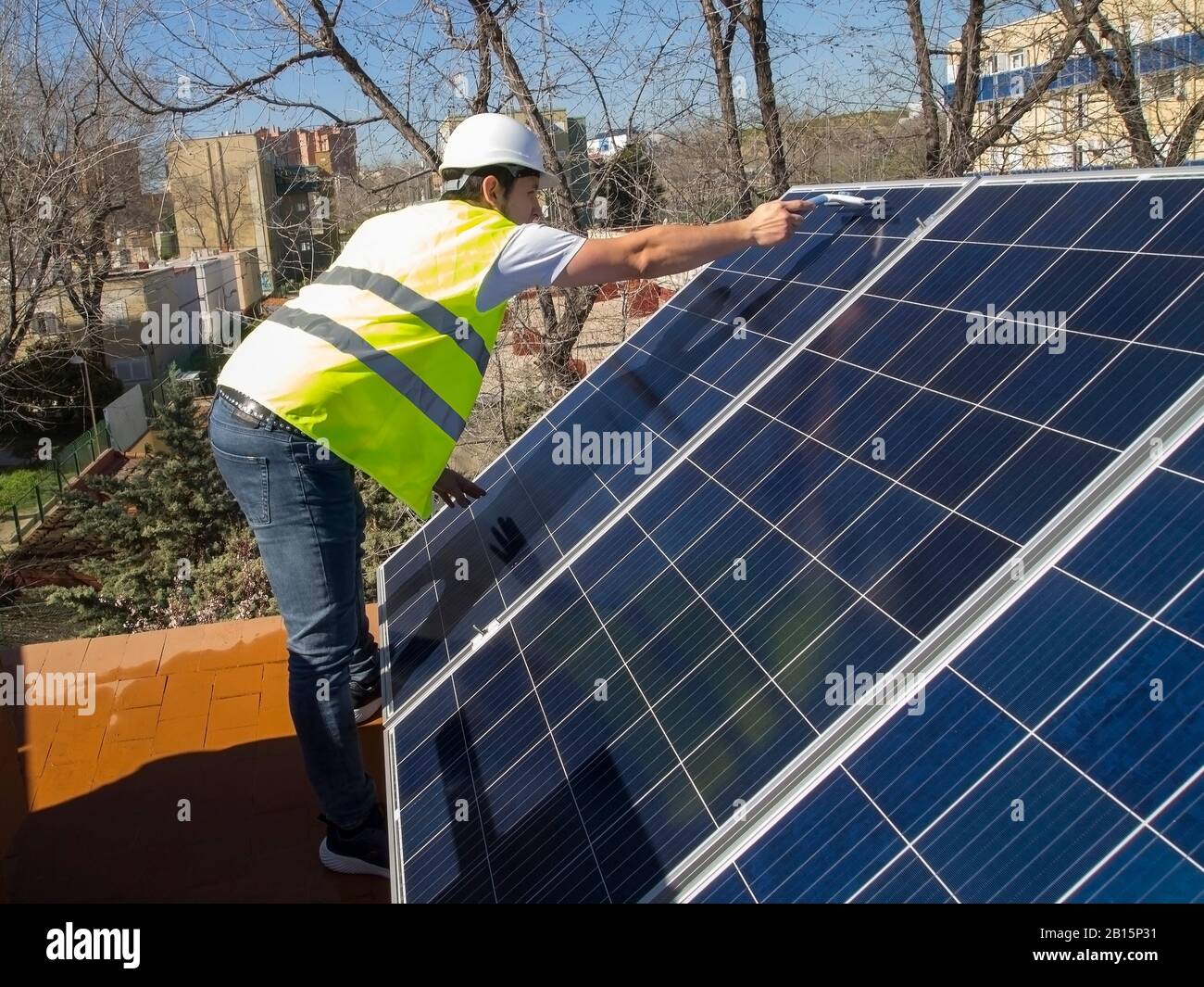 Caucasian attractive young technician cleaning solar panels with a ...