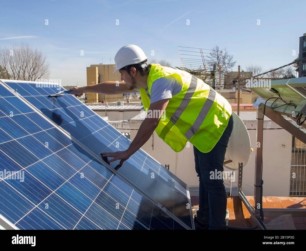 Caucasian attractive young technician cleaning solar panels with a ...