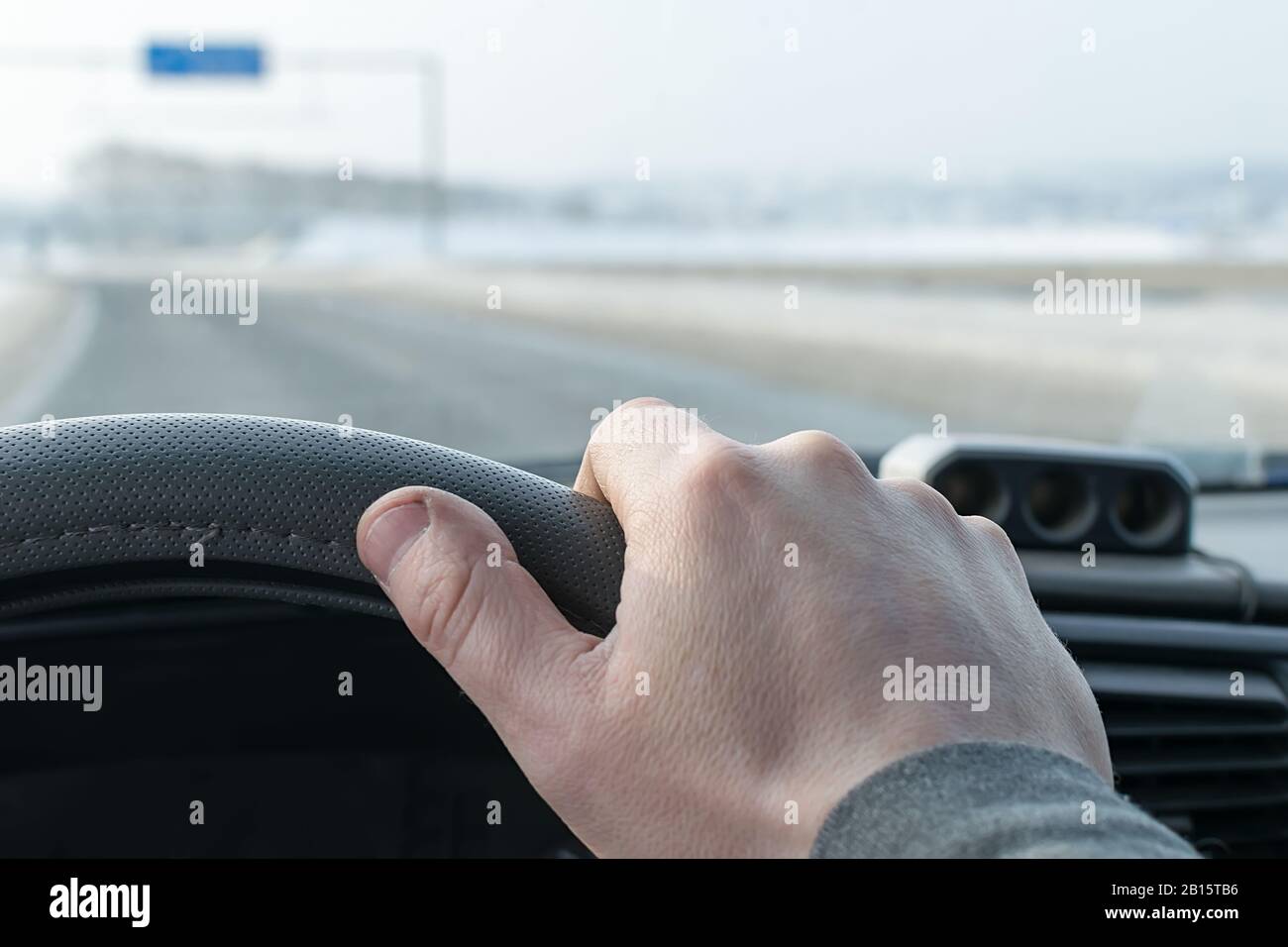 View of the driver hand on the steering wheel of a car that is driving ...
