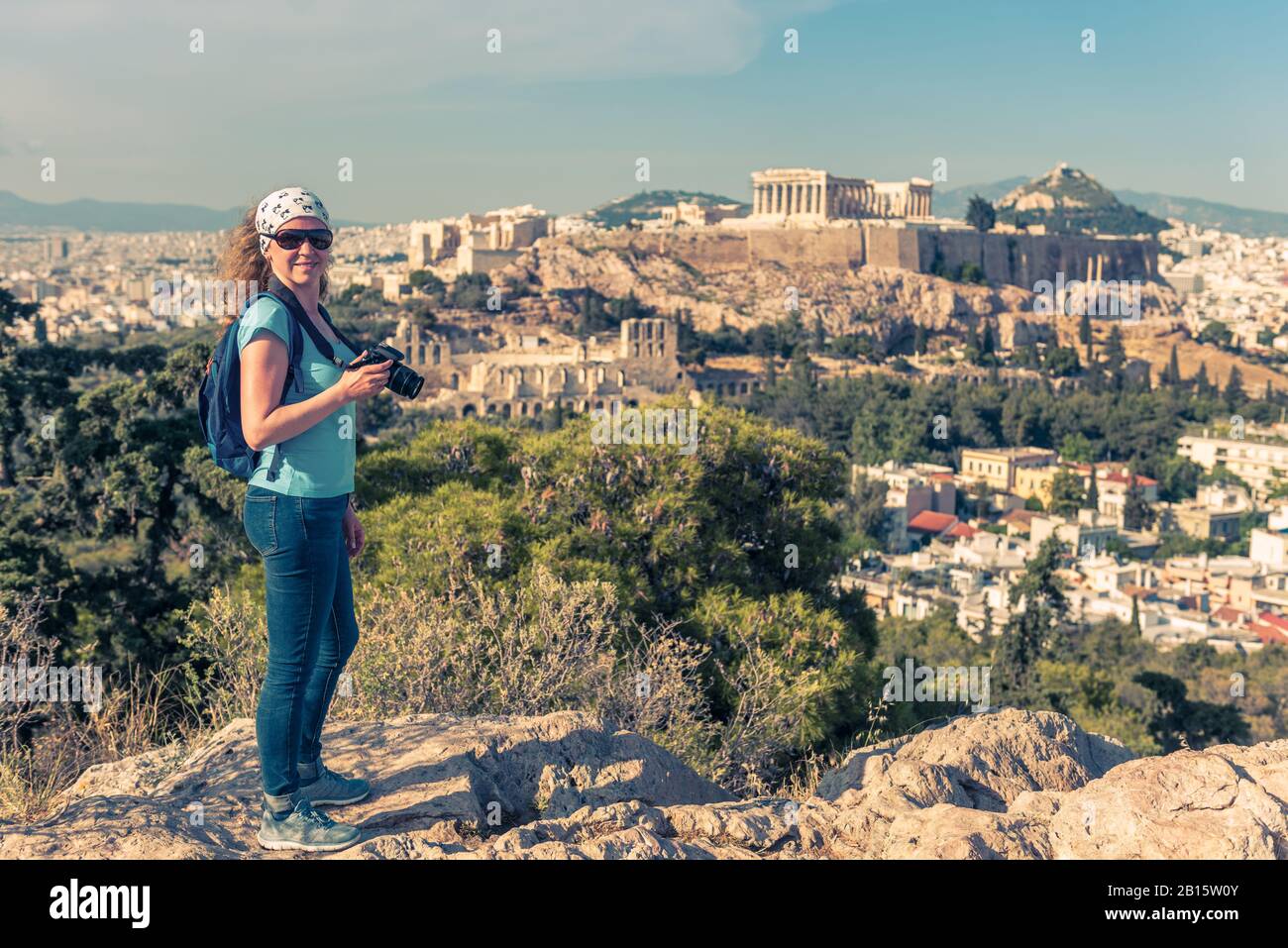 Cute young woman takes a picture of Acropolis from a top of hill ...
