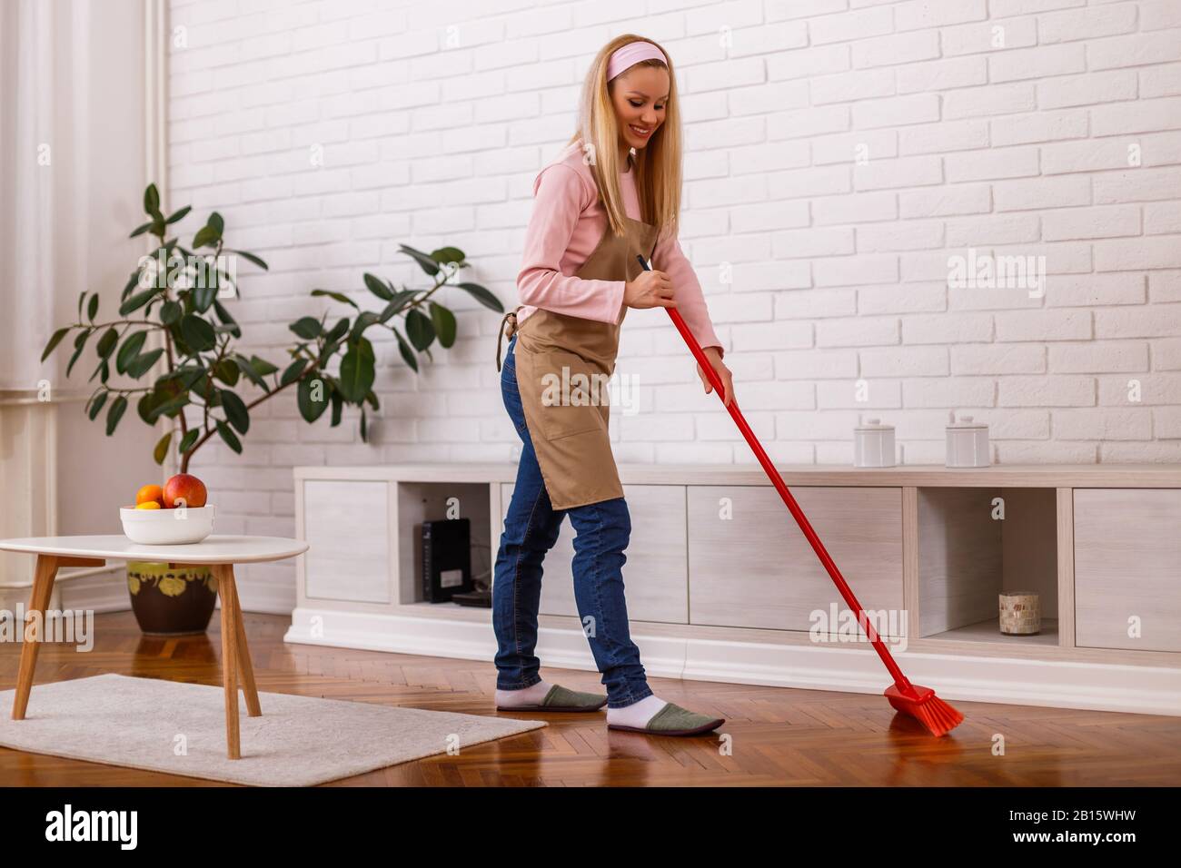 Beautiful housewife cleaning with broom her home Stock Photo - Alamy
