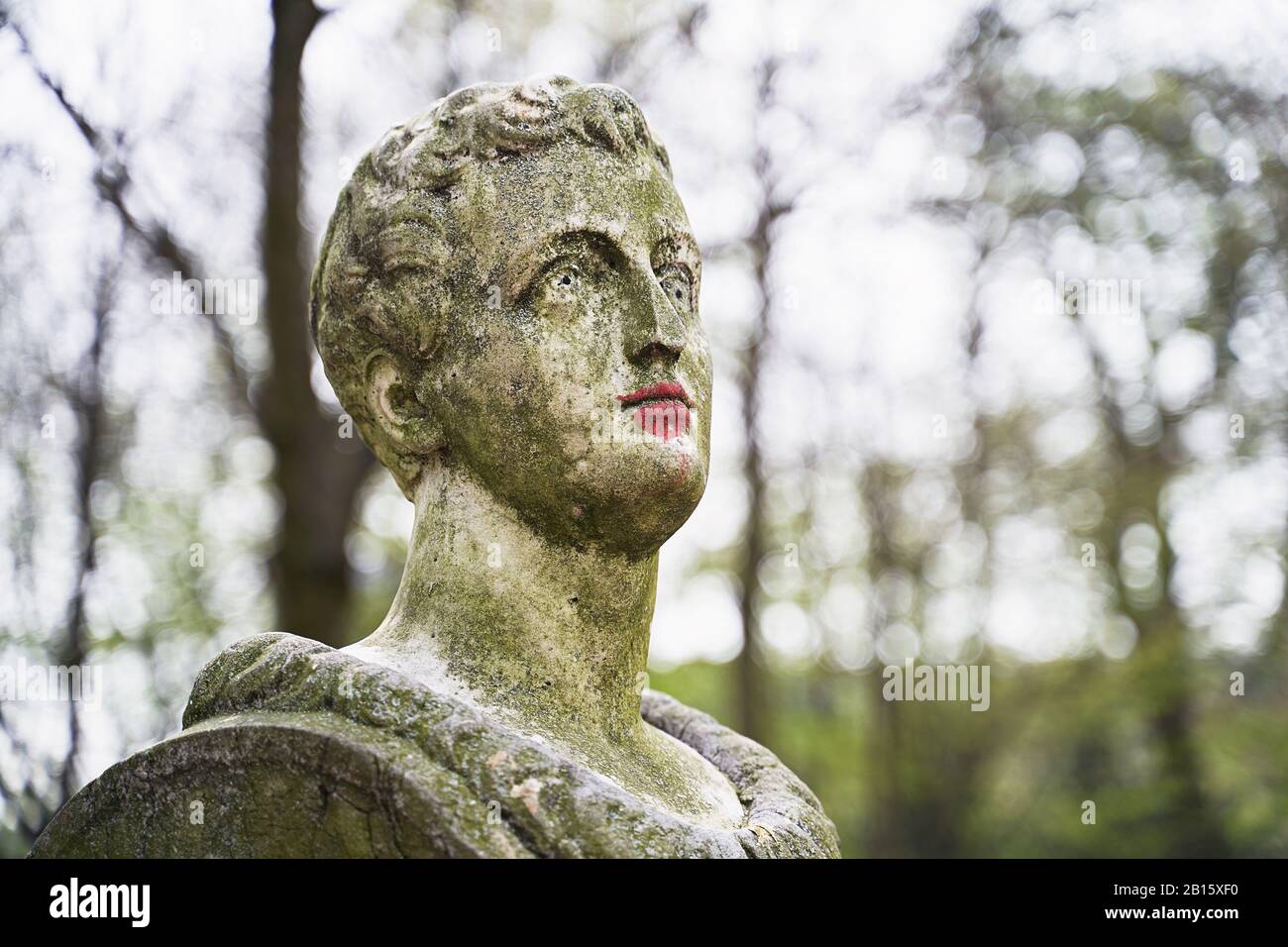 Old stone statue in Brussels public park with red painted colored lips ...
