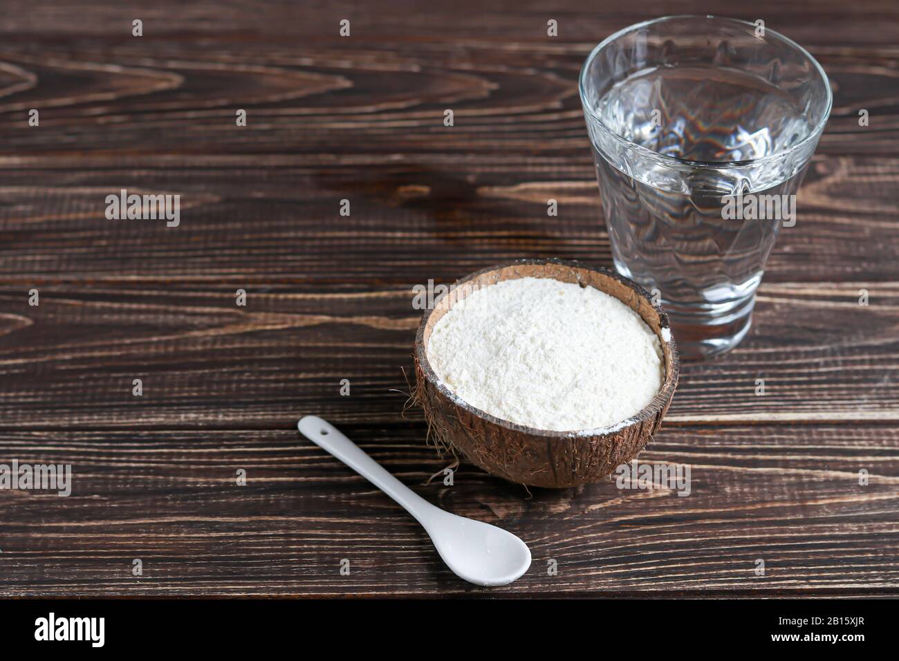 Collagen powder in half coconut with a spoon for measuring quantity ...