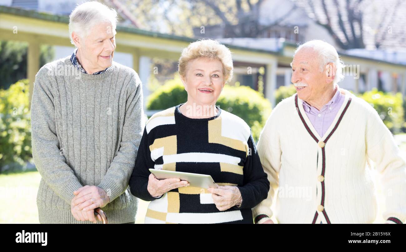 Group of three elderly people standing in the garden using tablet Stock ...