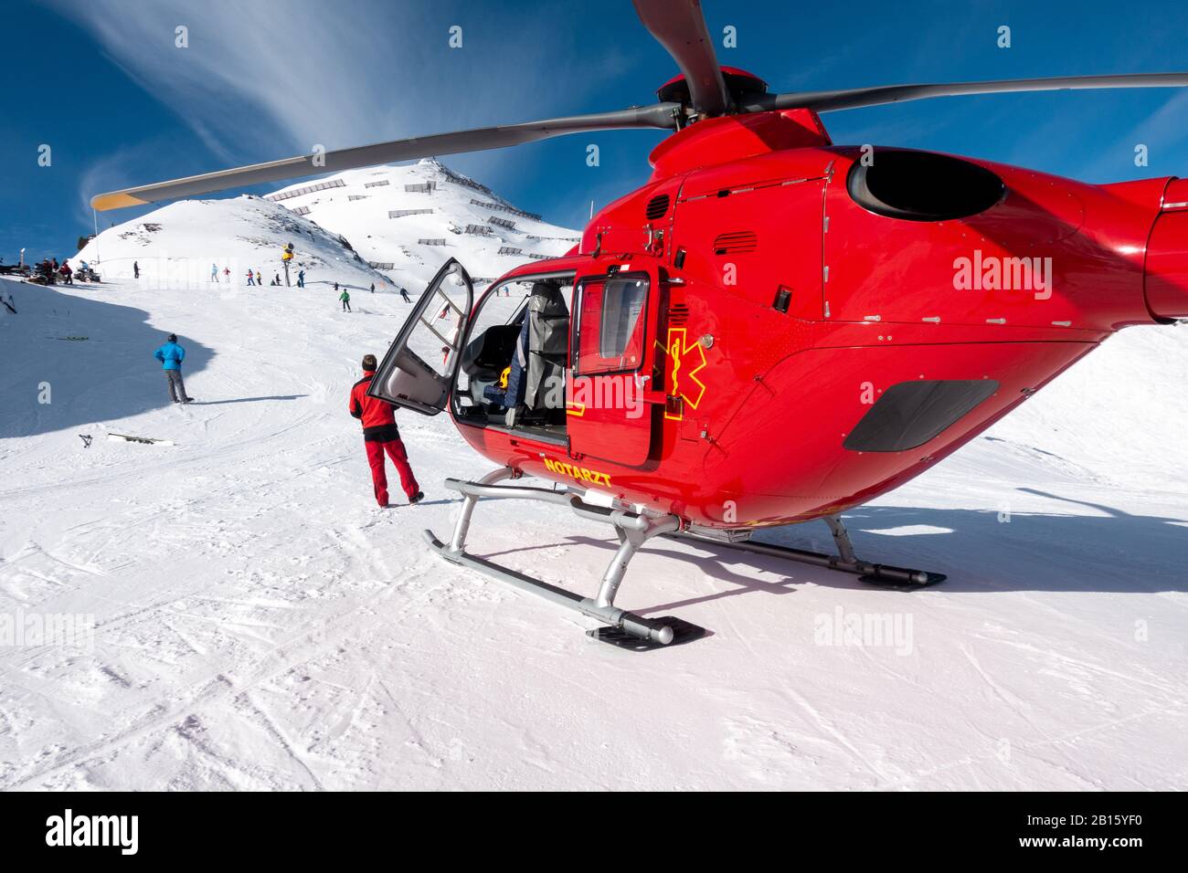 a red rescue helicopter stands on the snow-covered mountains of the ...
