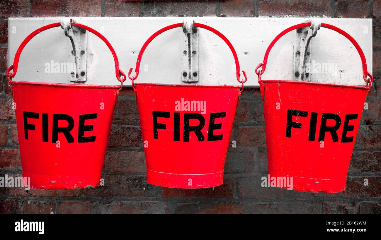 Three bright red emergency fire buckets on hangers Stock Photo - Alamy