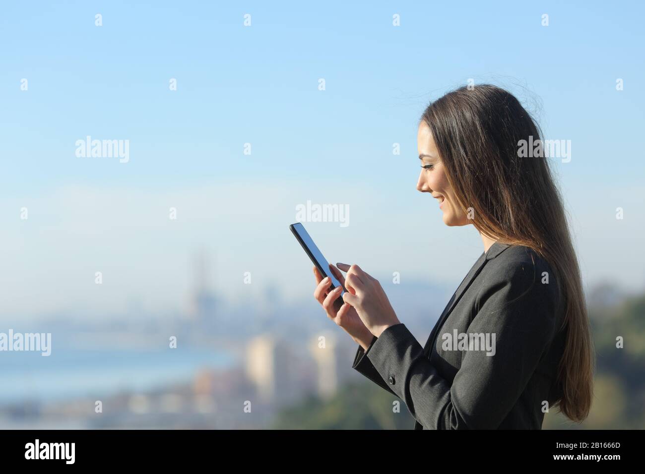 Side view portrait of a happy executive using smart phone in city ...