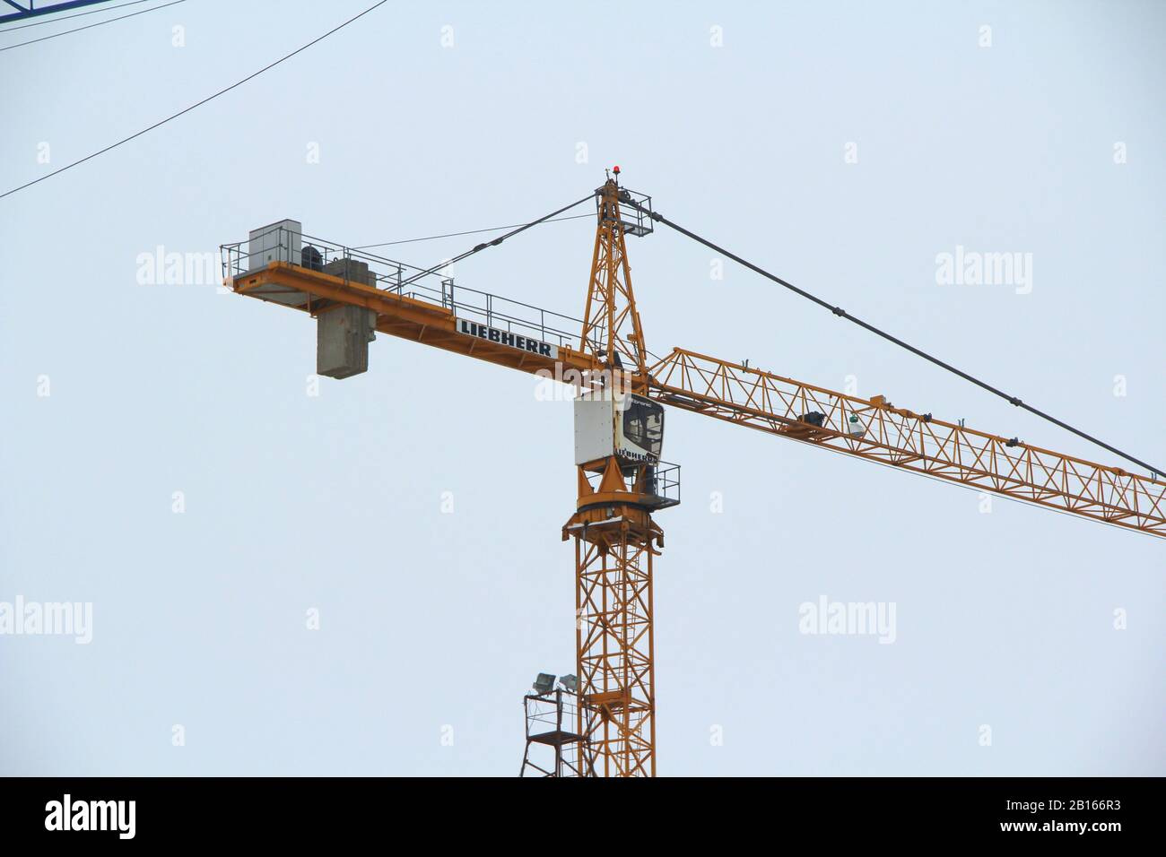 Tower crane works at a construction site against the white sky under ...
