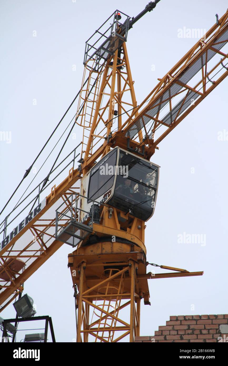 Tower crane works at a construction site against the sky. Crane driver ...