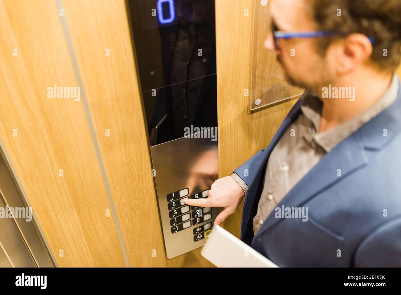 Man holding digital tablet while using elevator control panel Stock ...