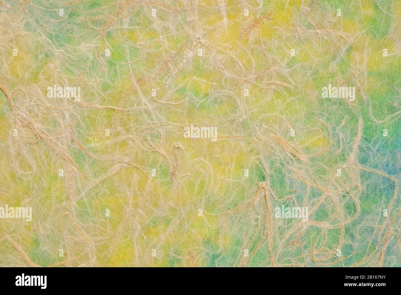 Natural Thai mulberry kozo paper against green, blue and yellow marbled ...