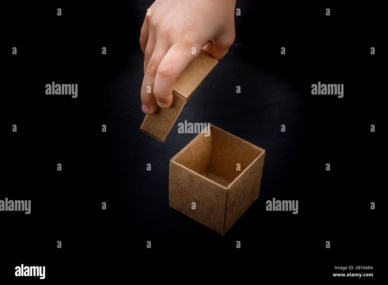 Hand opening a brown cardboard box on black backgrounds Stock Photo - Alamy