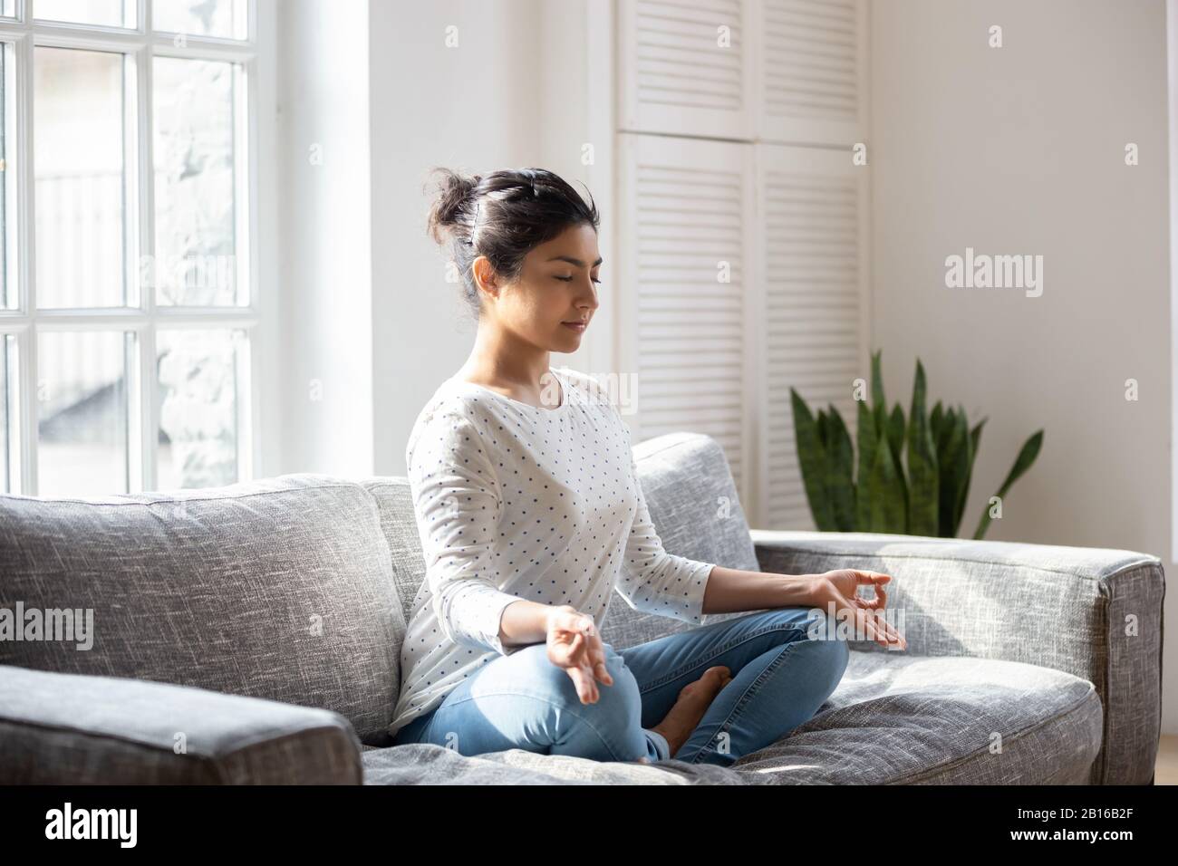 Indian female sitting on couch lotus pose do yoga exercise Stock Photo ...
