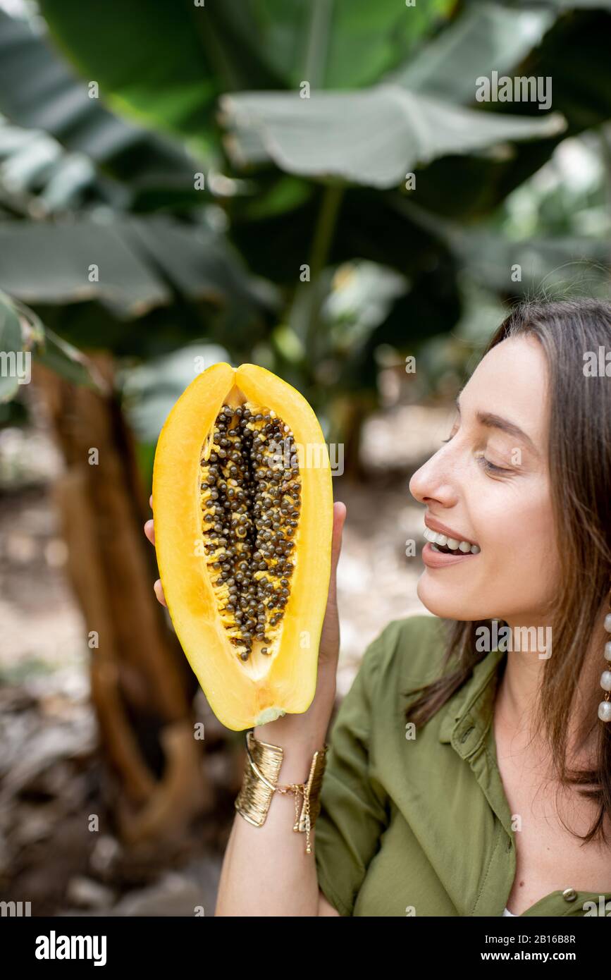 Closeup portrait of a young woman with sliced papaya fruit outdoors on ...