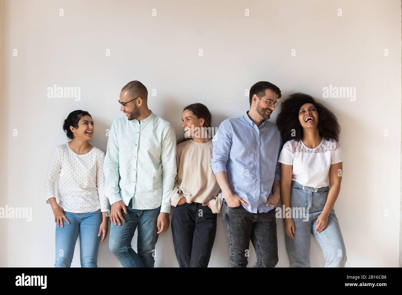 Five diverse best friends standing near wall indoors and laughing Stock ...