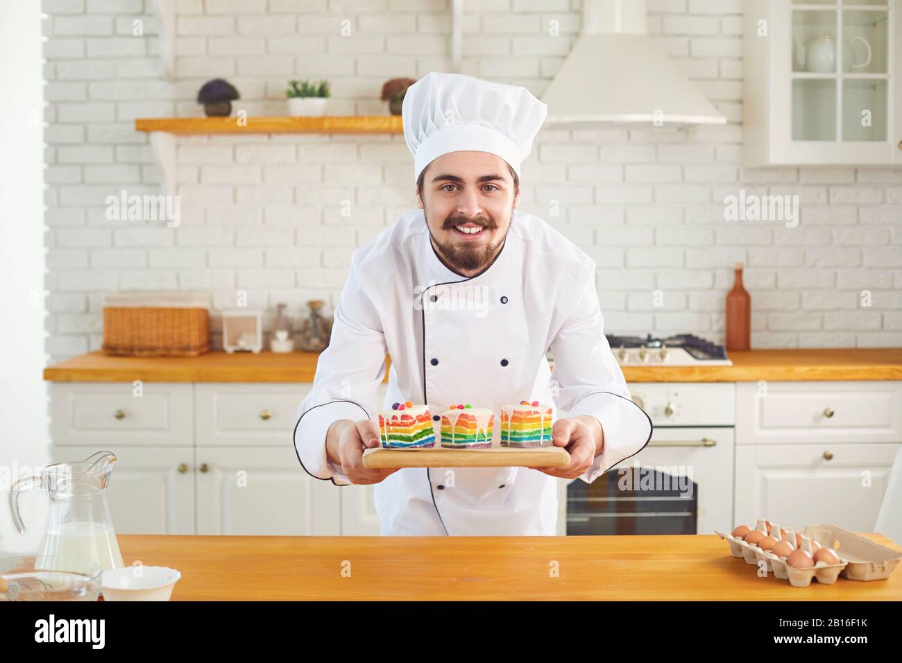 Confectioner man smiles while standing with cake in his hands at the ...