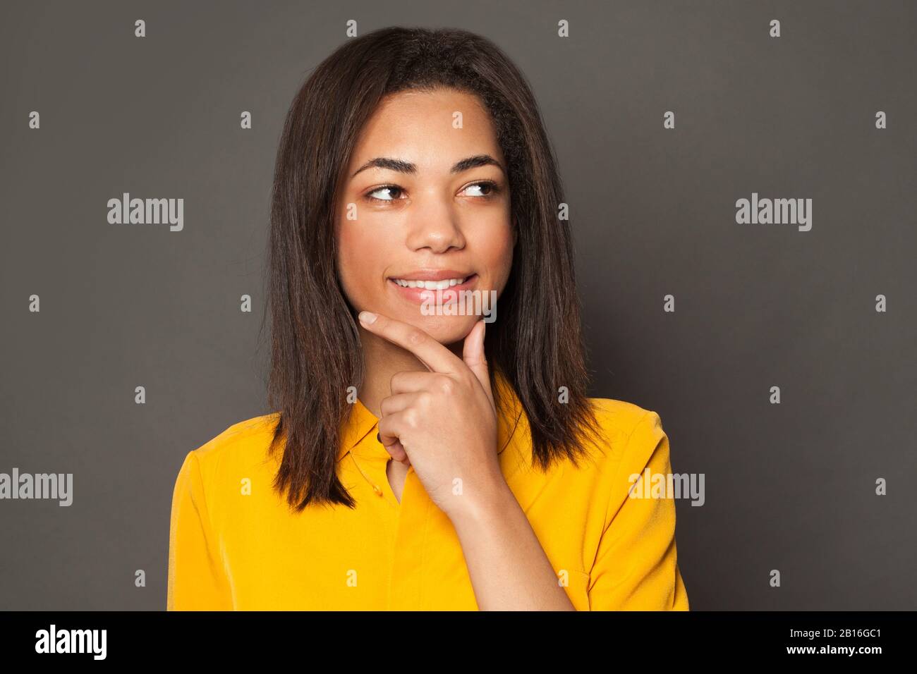 Young smart woman brunette thinking and smiling on gray background ...