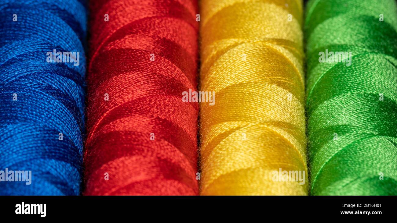Horizontal cones of bright colored sewing thread in Blue red yellow and ...
