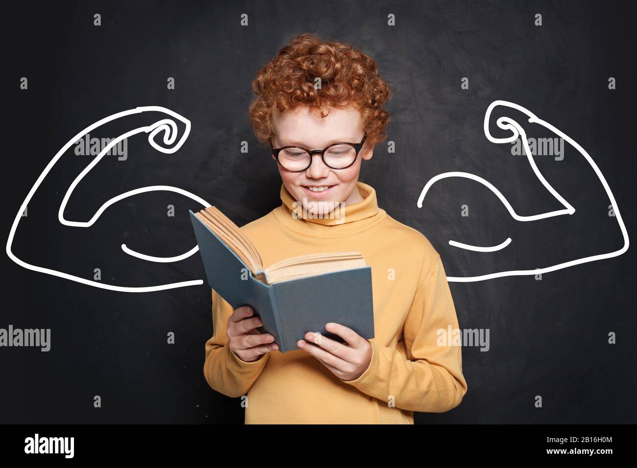 Cute strong little boy reading a book on chalkboard background Stock ...