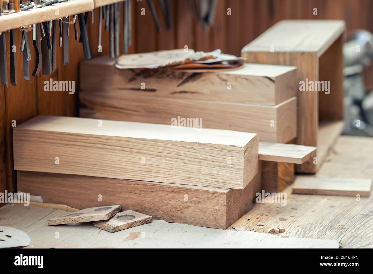 Oak wooden bar blocks materials stacked at carpentry woodwork workshop with tools and sawdust on ...