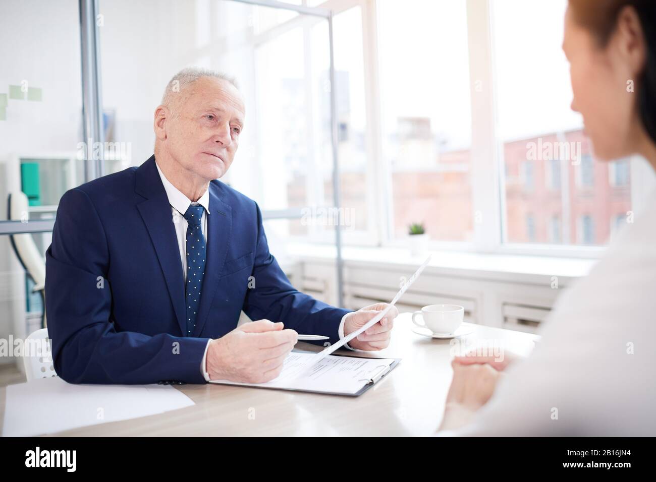 Portrait of successful senior businessman interviewing young woman for ...