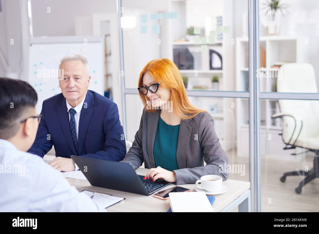 Portrait of two HR managers interviewing Asian young man for job ...