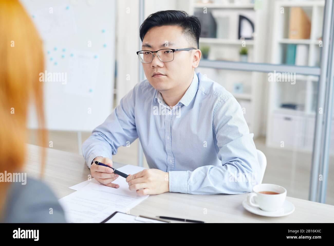 Portrait of young Asian man answering questions during job interview ...