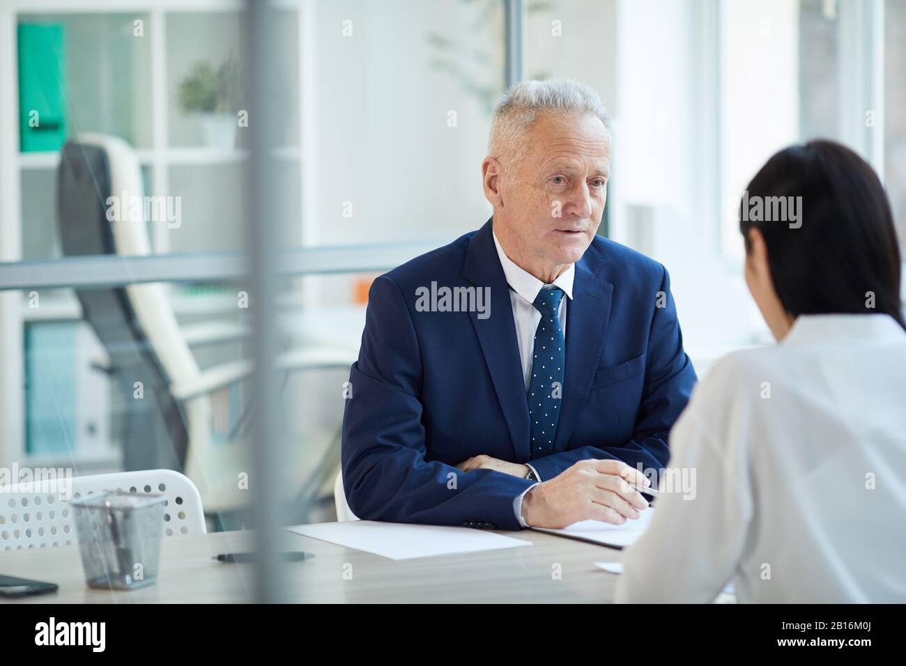 Portrait of successful senior businessman interviewing young woman for ...