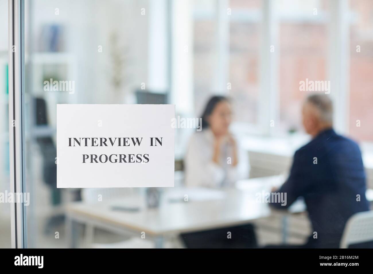 Background image of job interview in progress sign on glass door in ...