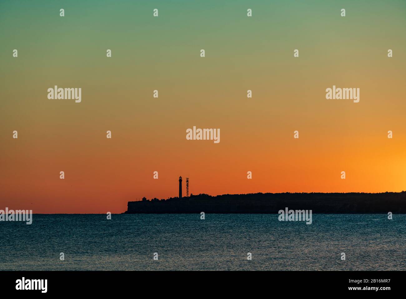 Evening sunlight on coast, pink and golden clouds and wind turbine. Sky ...