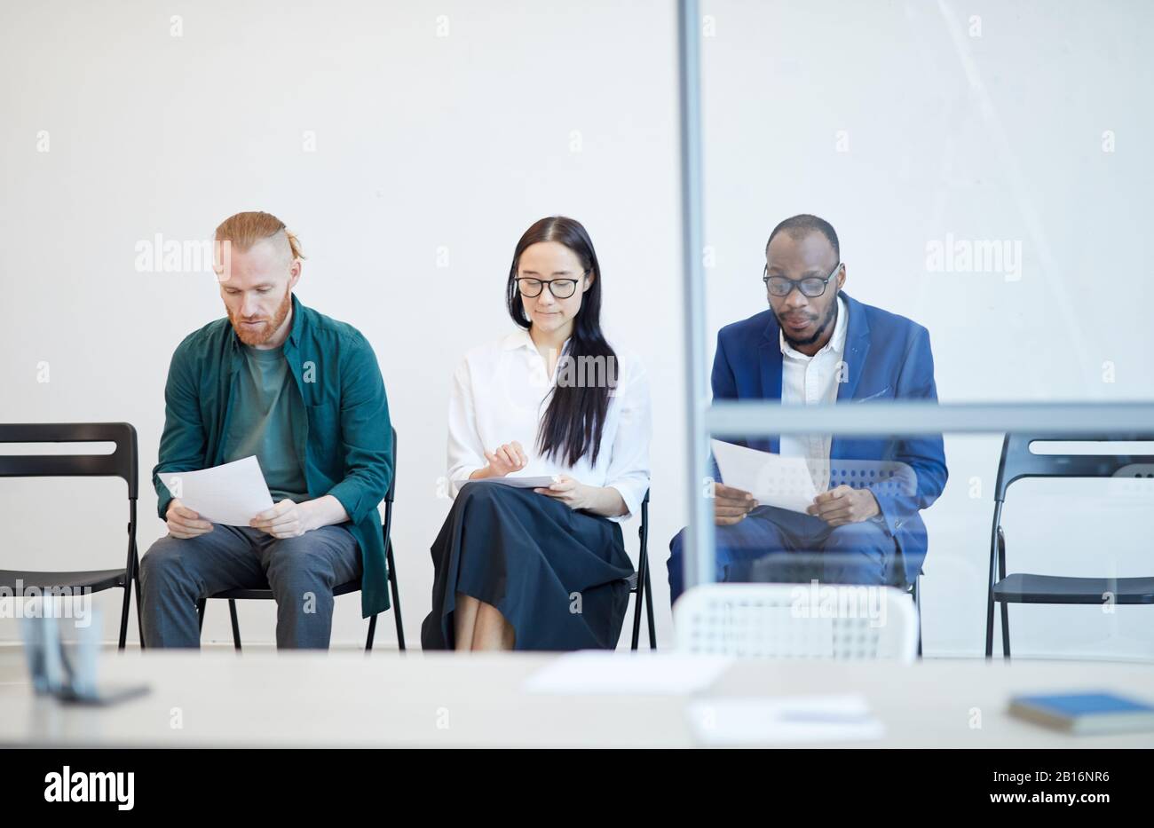 Multi-ethnic group of people waiting in line for job interview and ...