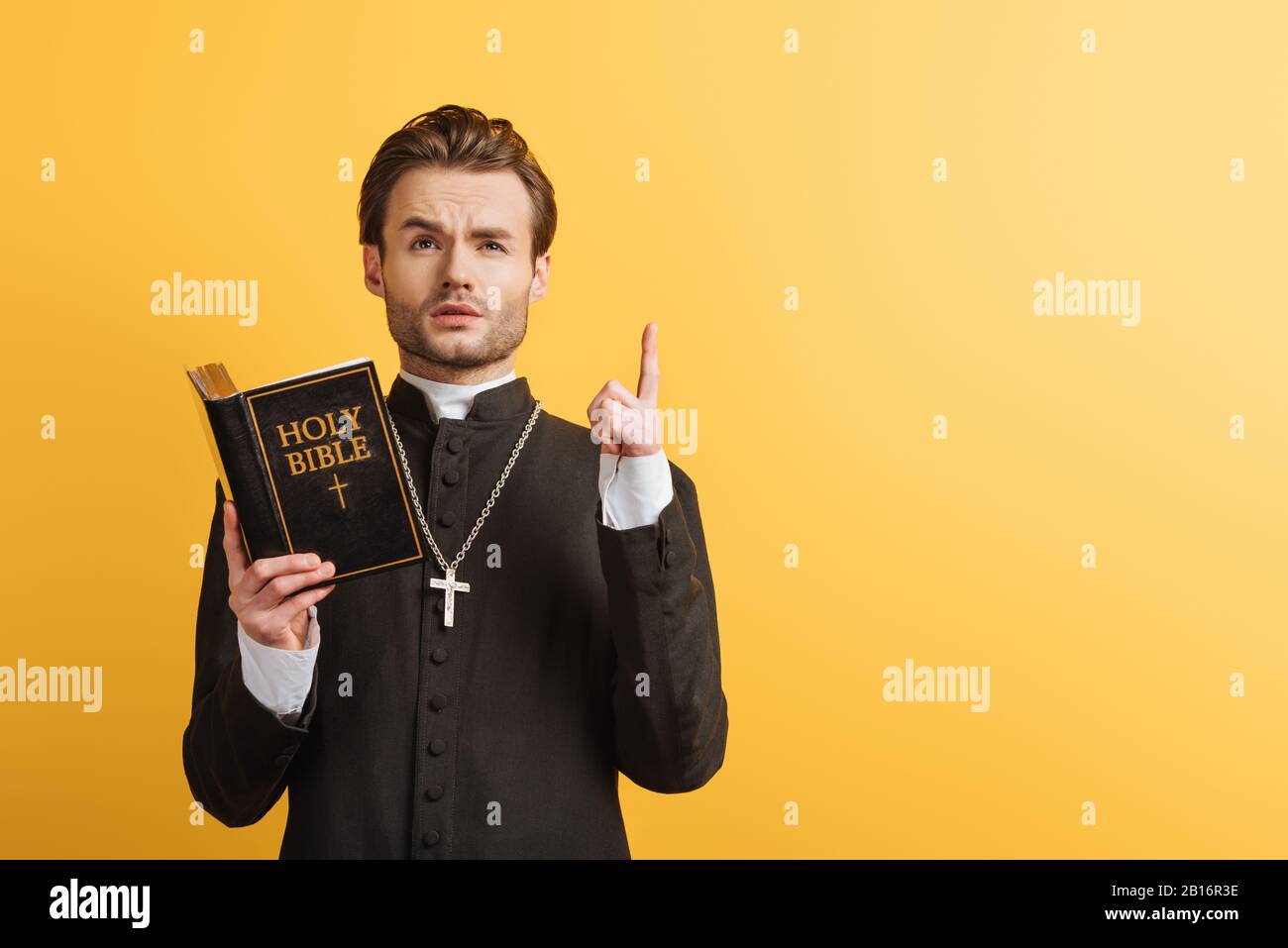 thoughtful catholic priest looking up and showing idea sign while ...
