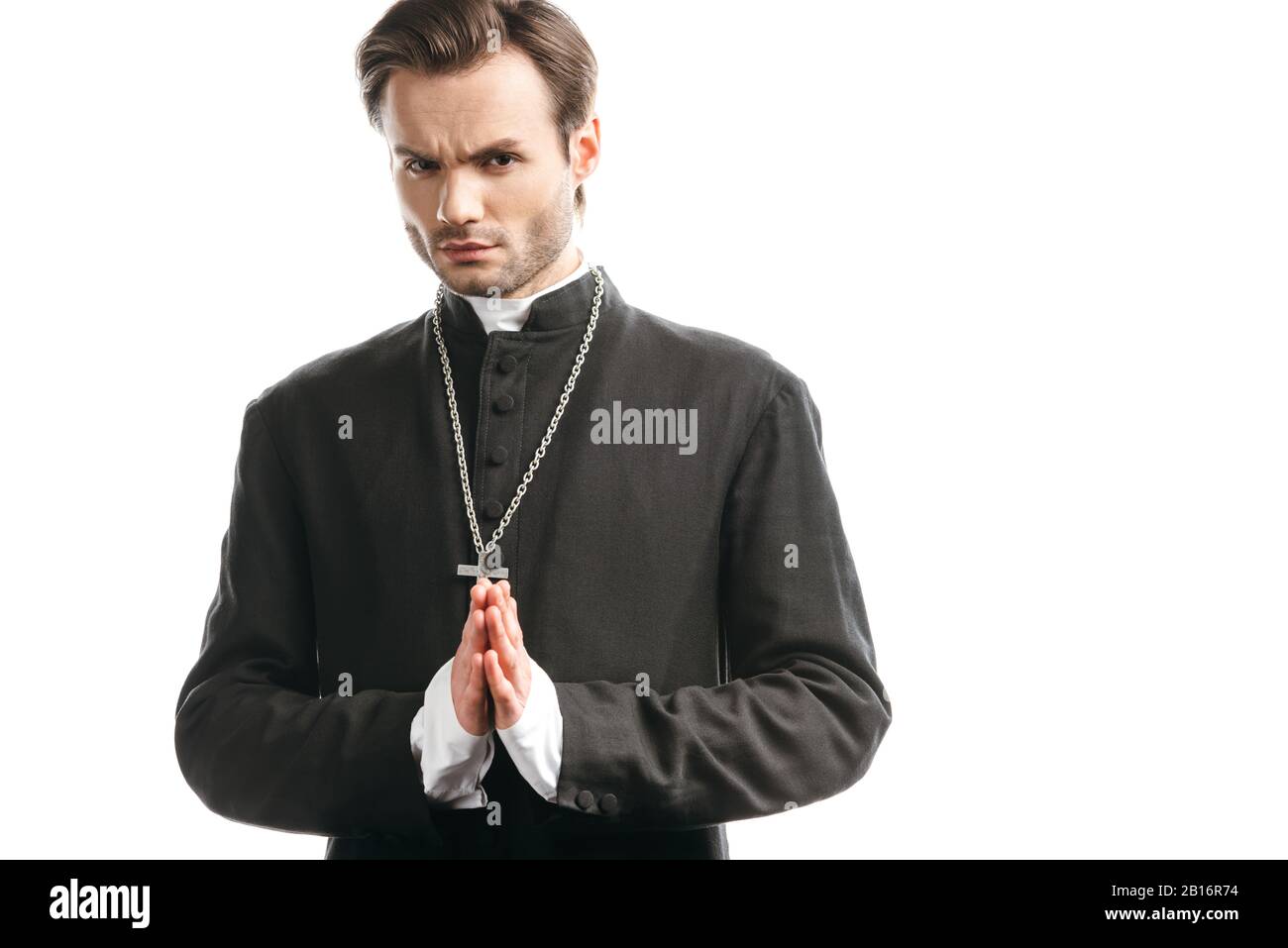serious, strict catholic priest with praying hands looking at camera ...