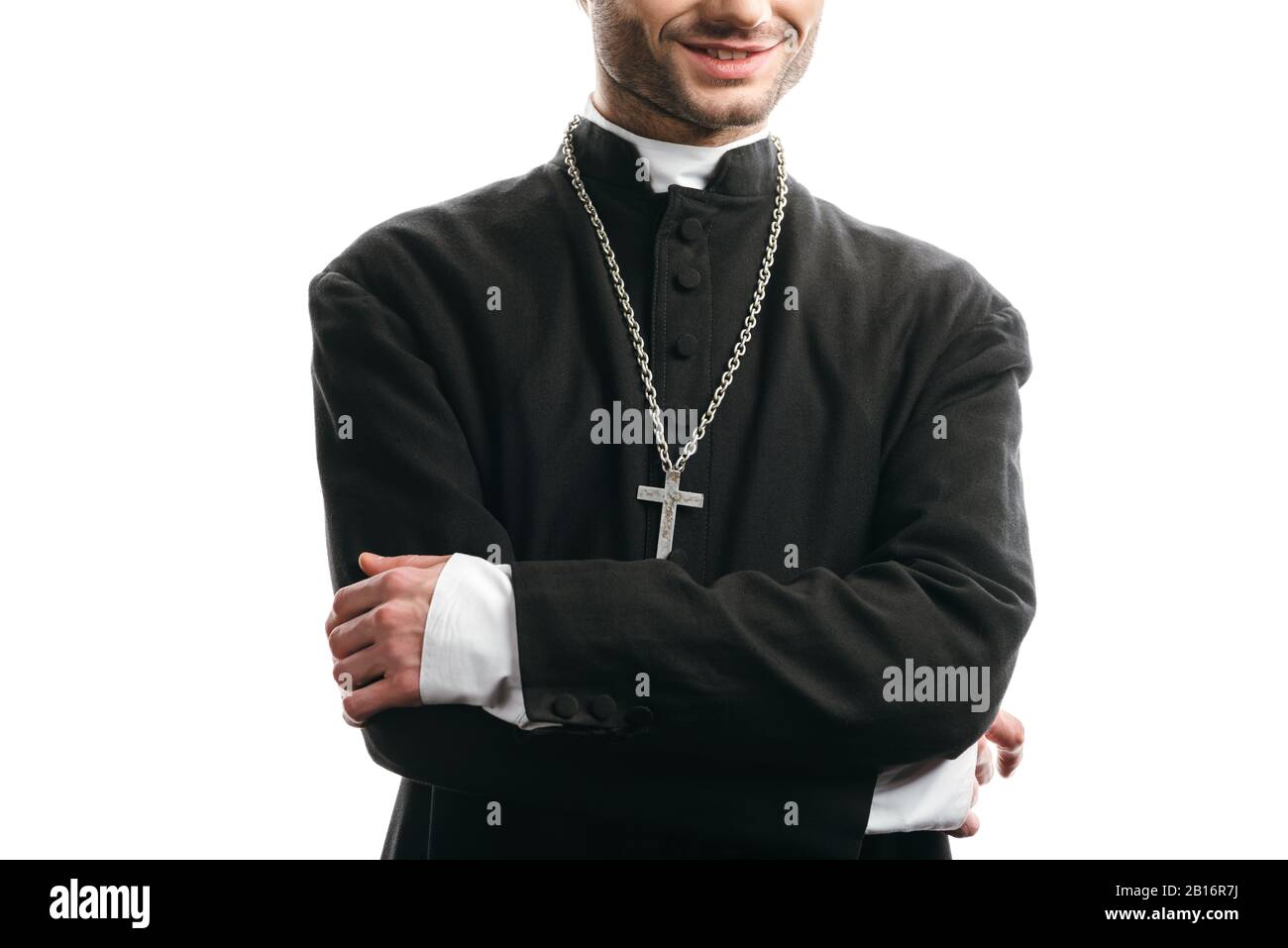 cropped view of smiling catholic priest standing with crossed arms ...