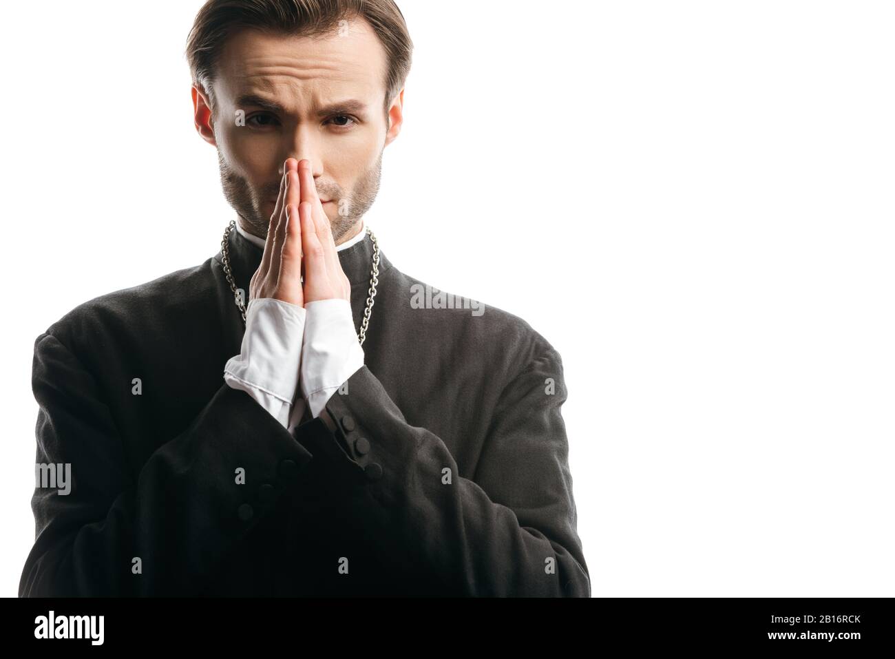 serious, concentrated catholic priest praying while looking at camera ...