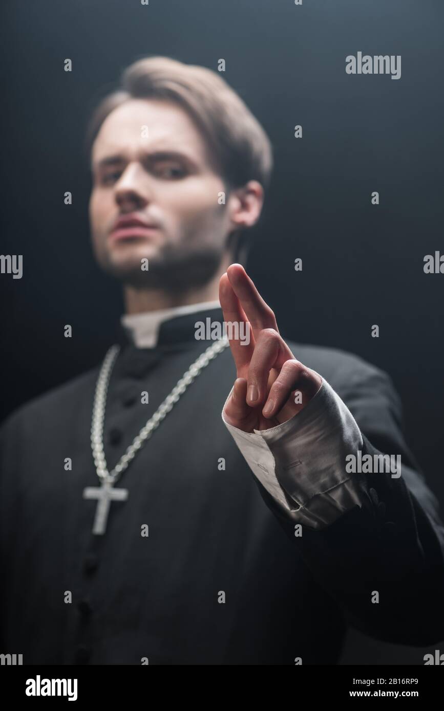 low angle view of confident catholic priest showing blessing gesture ...
