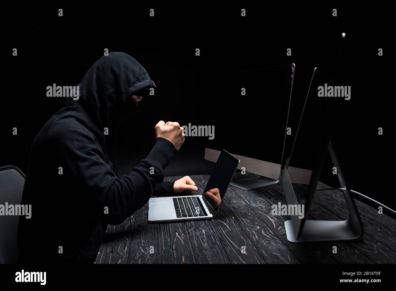 angry hacker with clenched fist near laptop and computer monitors with ...
