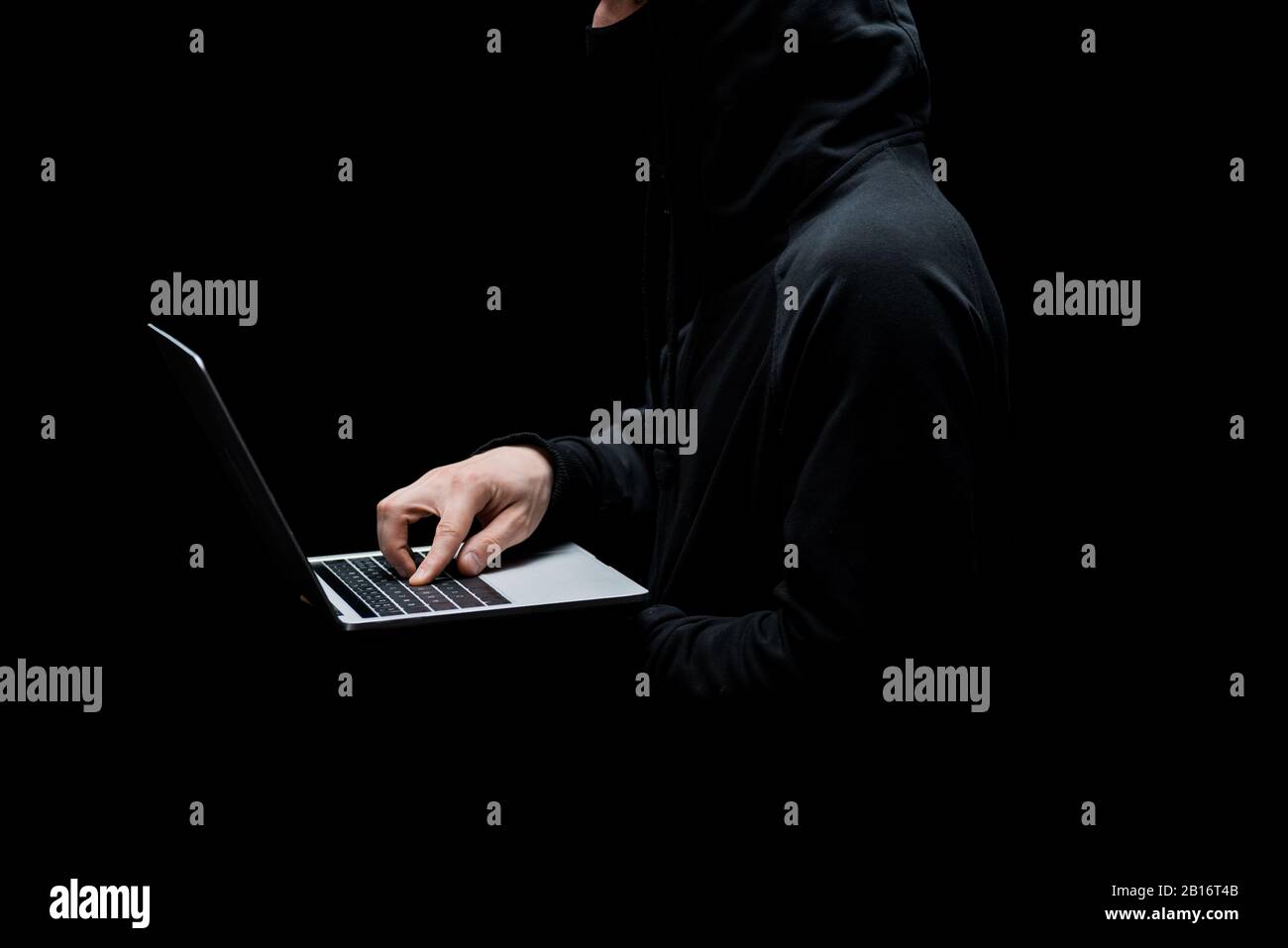 cropped view of hacker in hood using laptop isolated on black Stock ...
