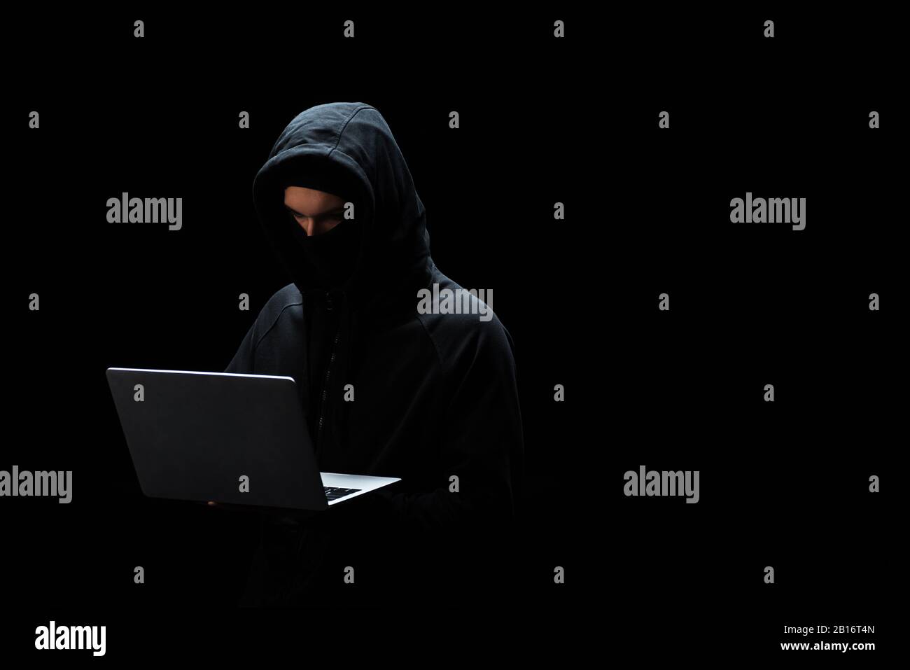 hacker in mask and hood using laptop isolated on black Stock Photo - Alamy