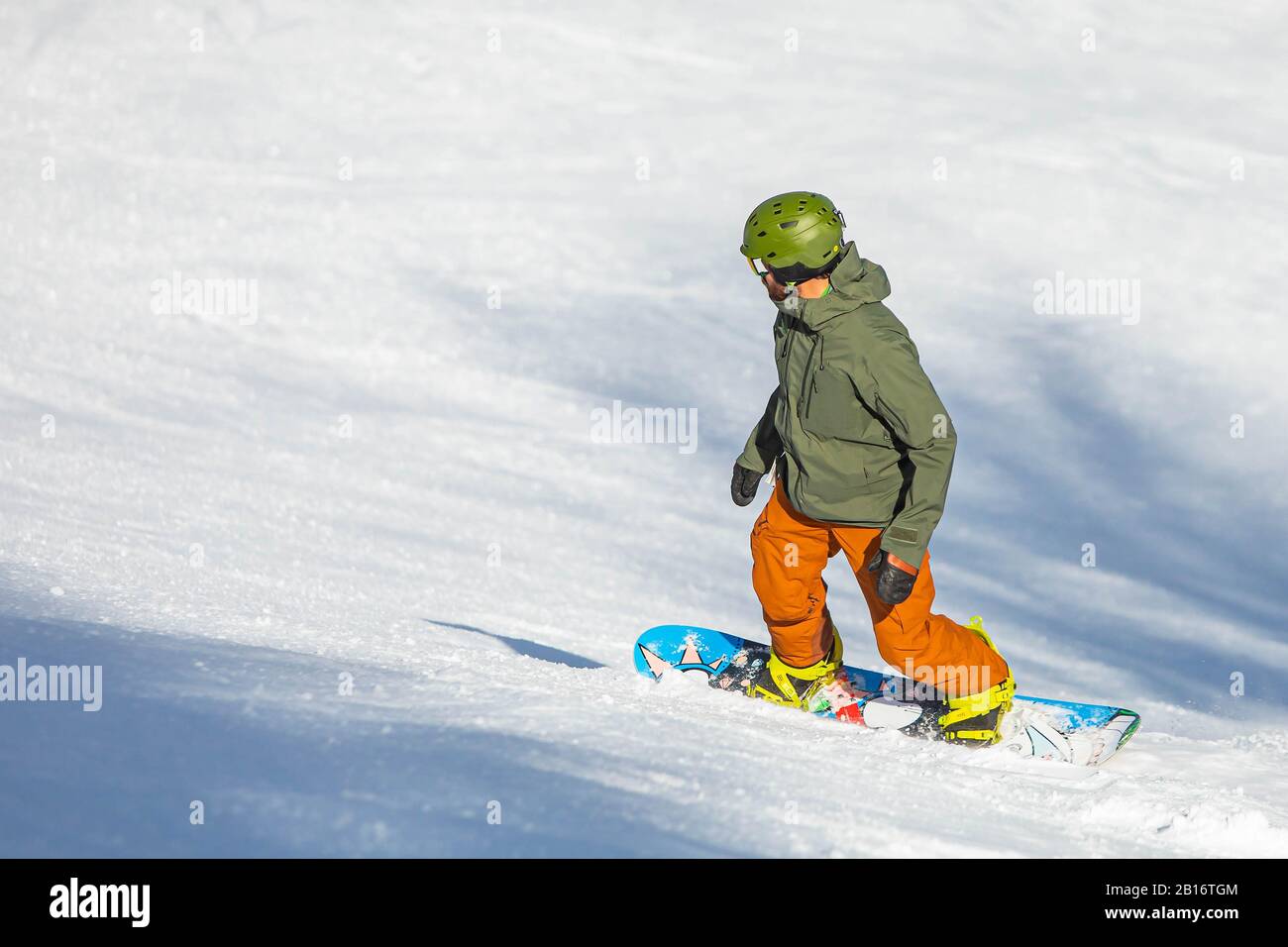 Snowboarder having fun riding hill at ski resort from side Stock Photo ...