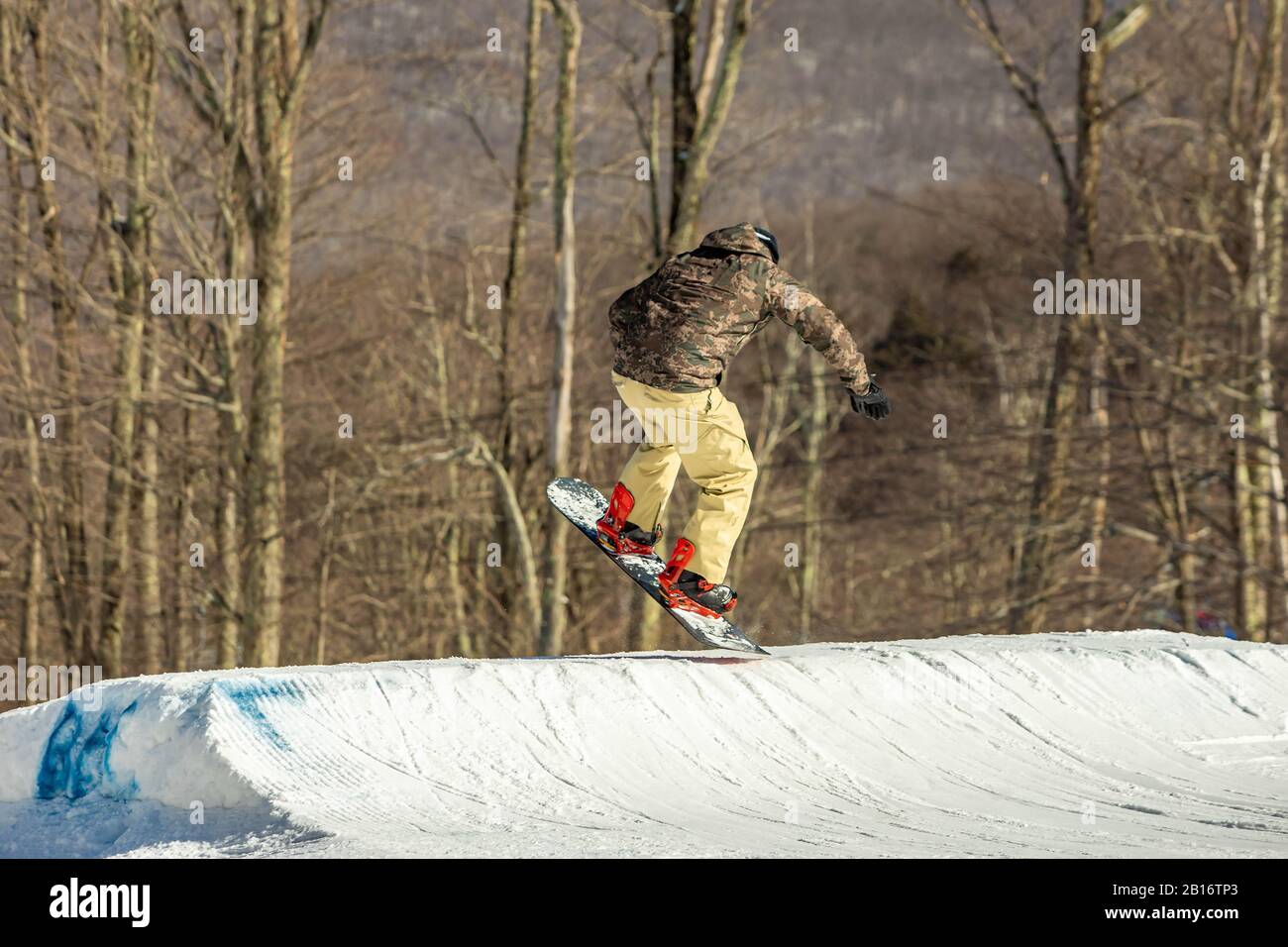 Snowboarder having fun jumping at ski resort in the air from the back ...