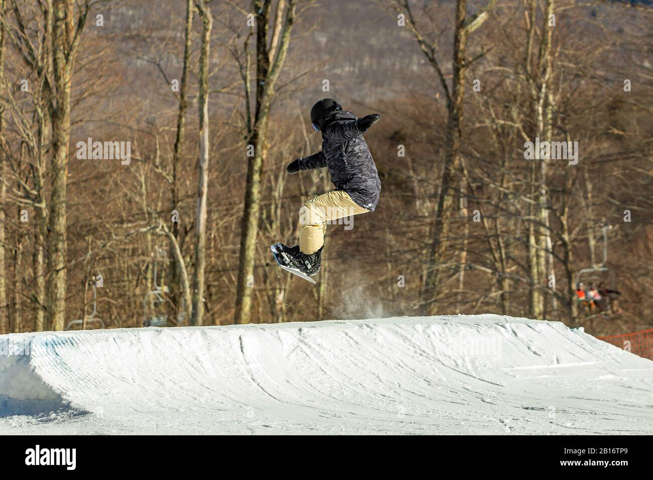Snowboarder having fun jumping at ski resort in the air from the back ...