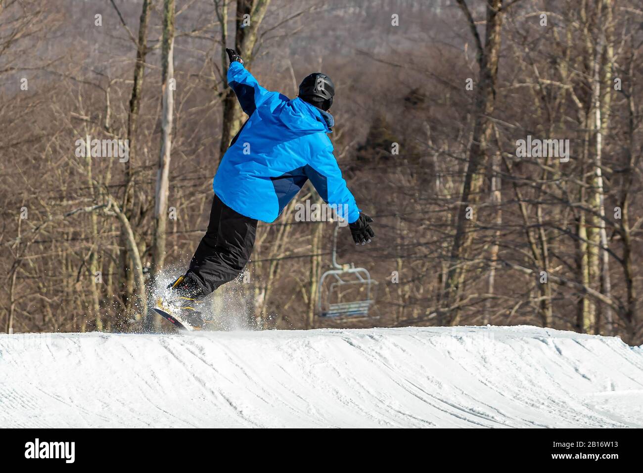 Snowboarder having fun jumping at ski resort in the air from the back ...