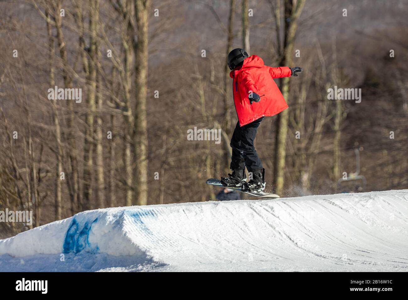 Snowboarder having fun jumping at ski resort in the air from the back ...