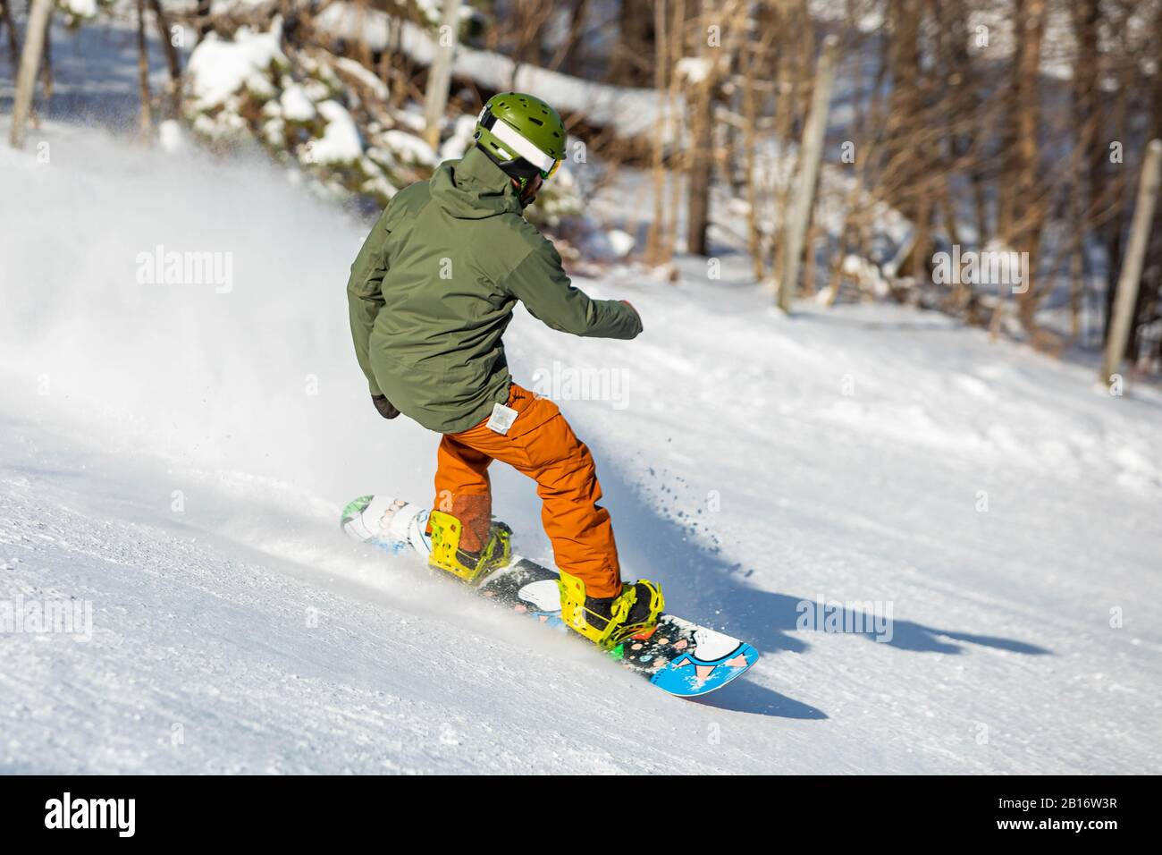 Snowboarder having fun riding hill at ski resort from side Stock Photo ...