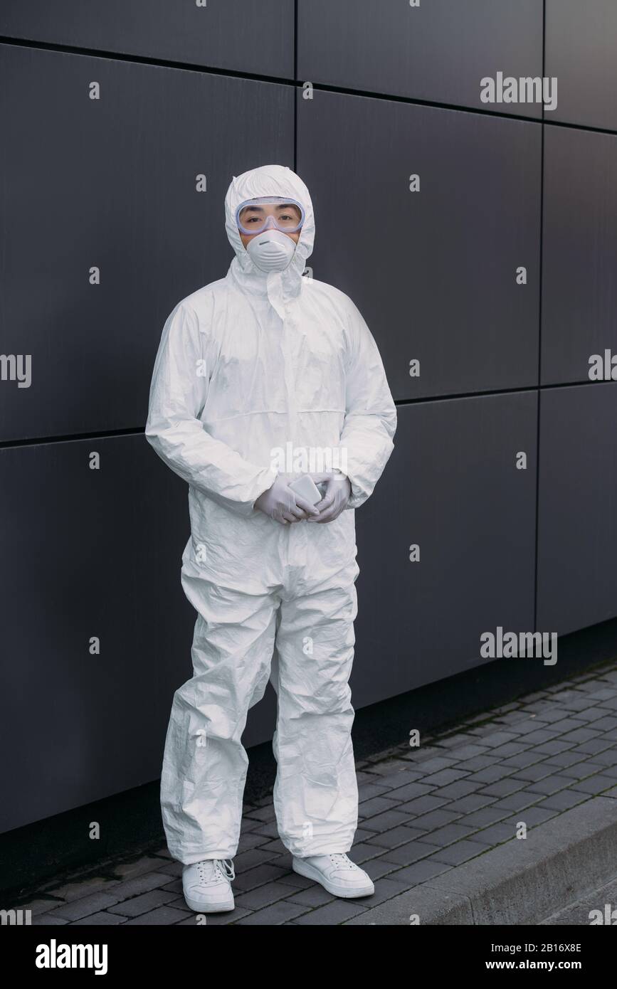 asian epidemiologist in hazmat suit and respirator mask looking at ...