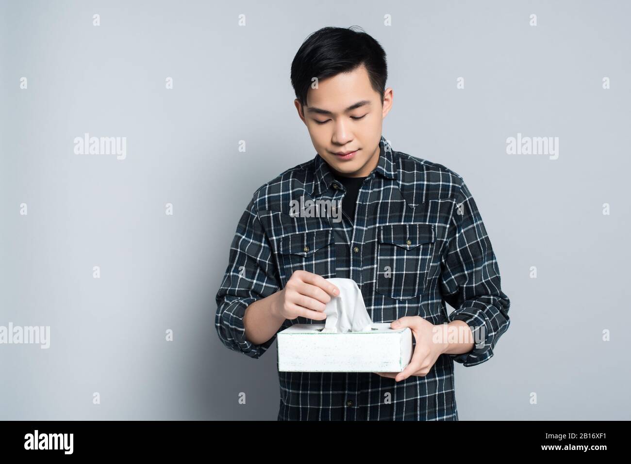 young asian man holding pack of paper napkins while suffering from ...
